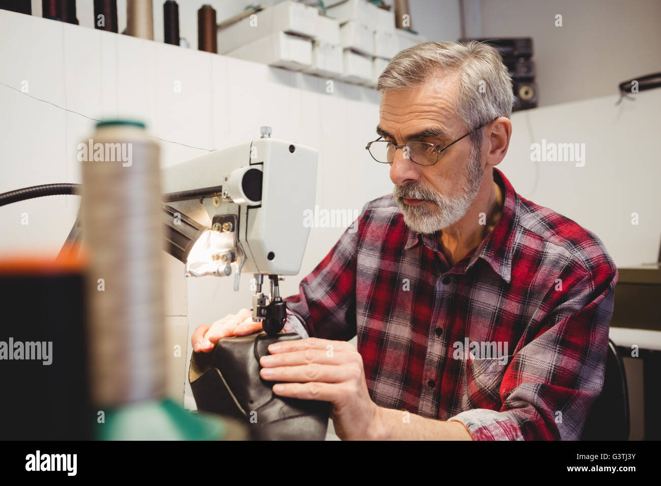 Concentrated cobbler using a sewing machine Stock Photo - Alamy