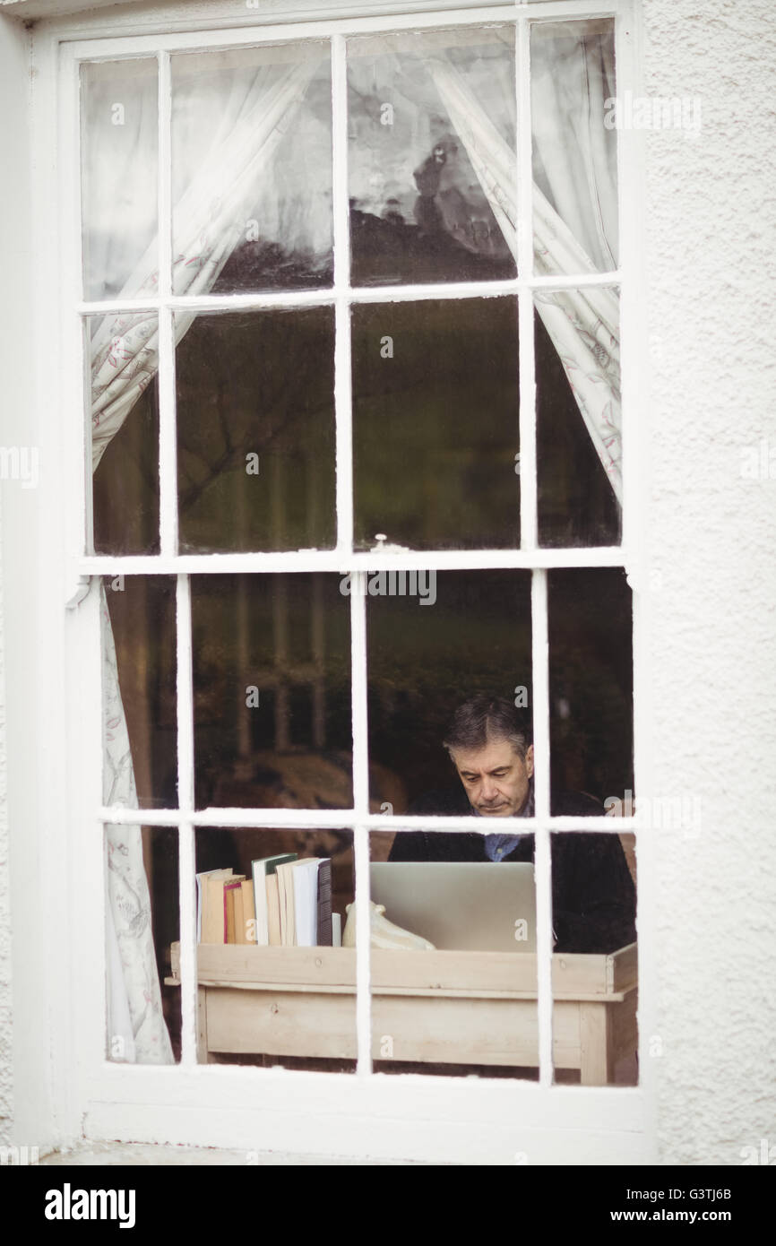 Man working on laptop at window Stock Photo - Alamy
