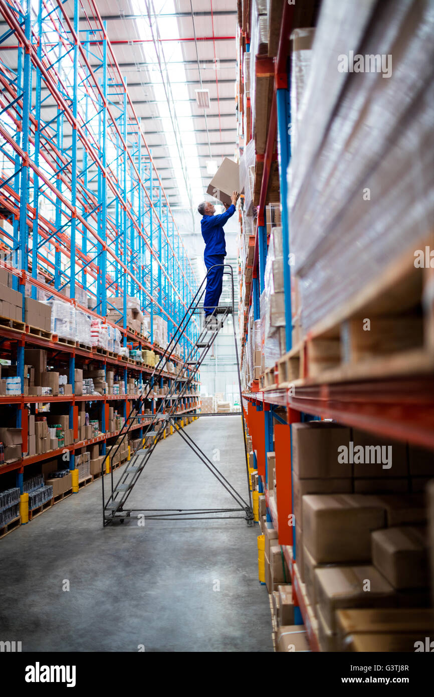 Man worker putting a box on a rack Stock Photo - Alamy