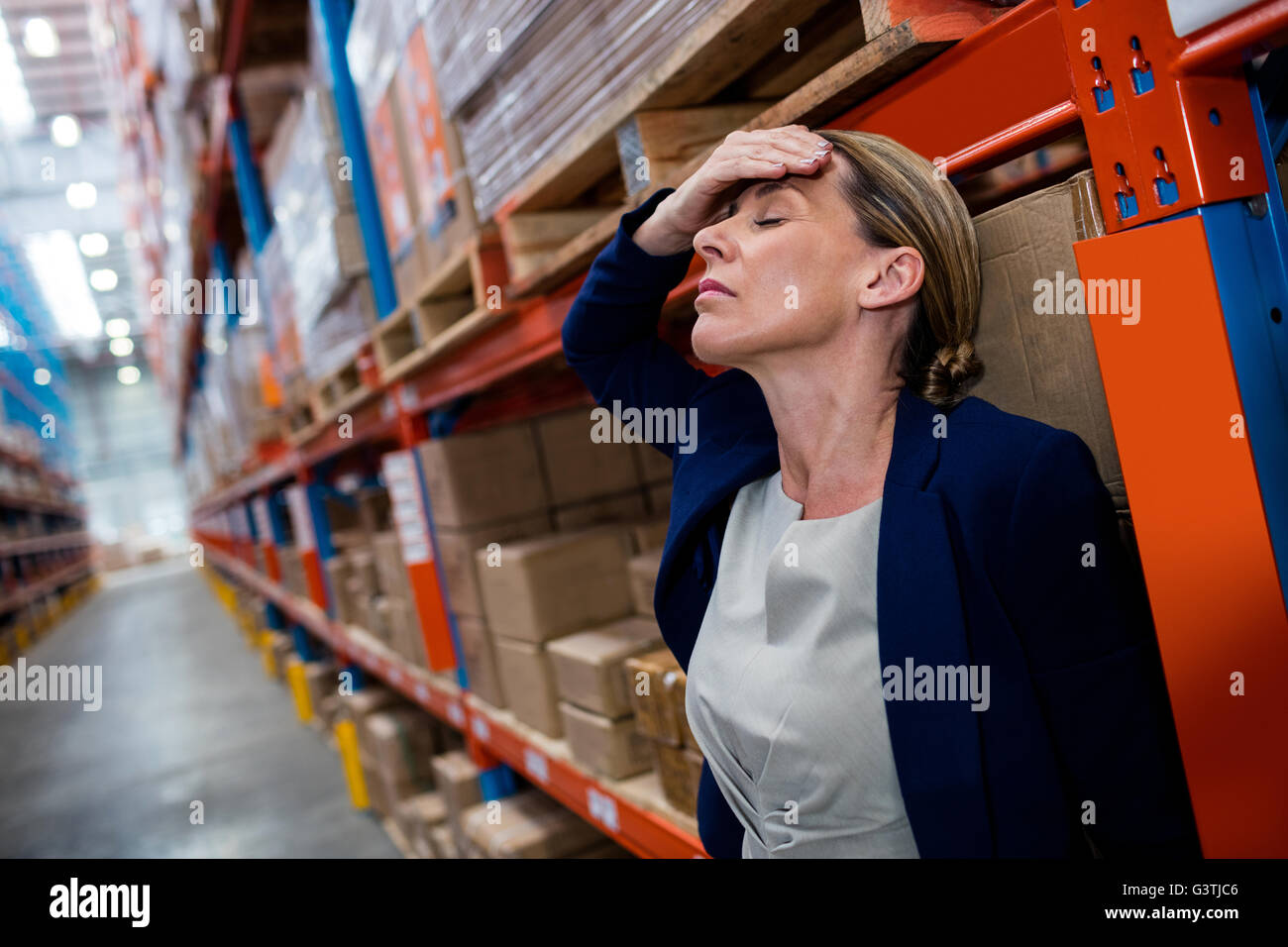 Exhausted warehouse manager`leaning on a rack Stock Photo - Alamy