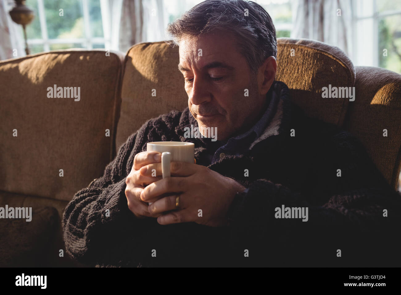 Portrait of man drinking cup of tea while relaxing Stock Photo - Alamy