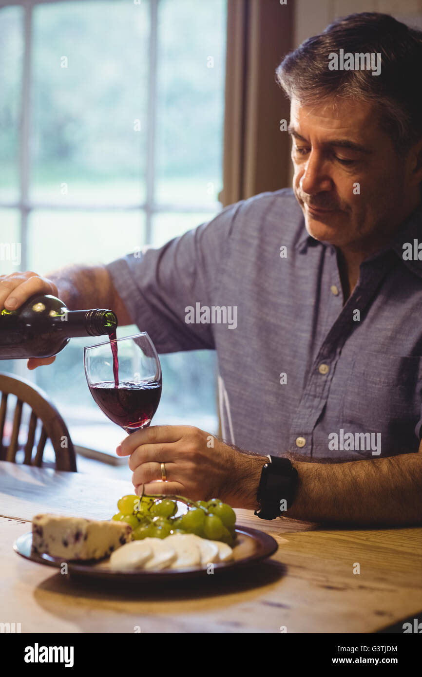 Portrait of mature man filling a glass of wine Stock Photo - Alamy