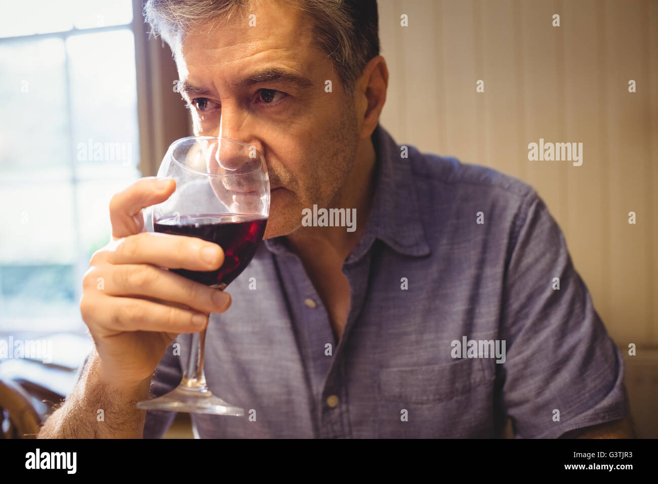 Concentrated mature man tasting red wine Stock Photo - Alamy