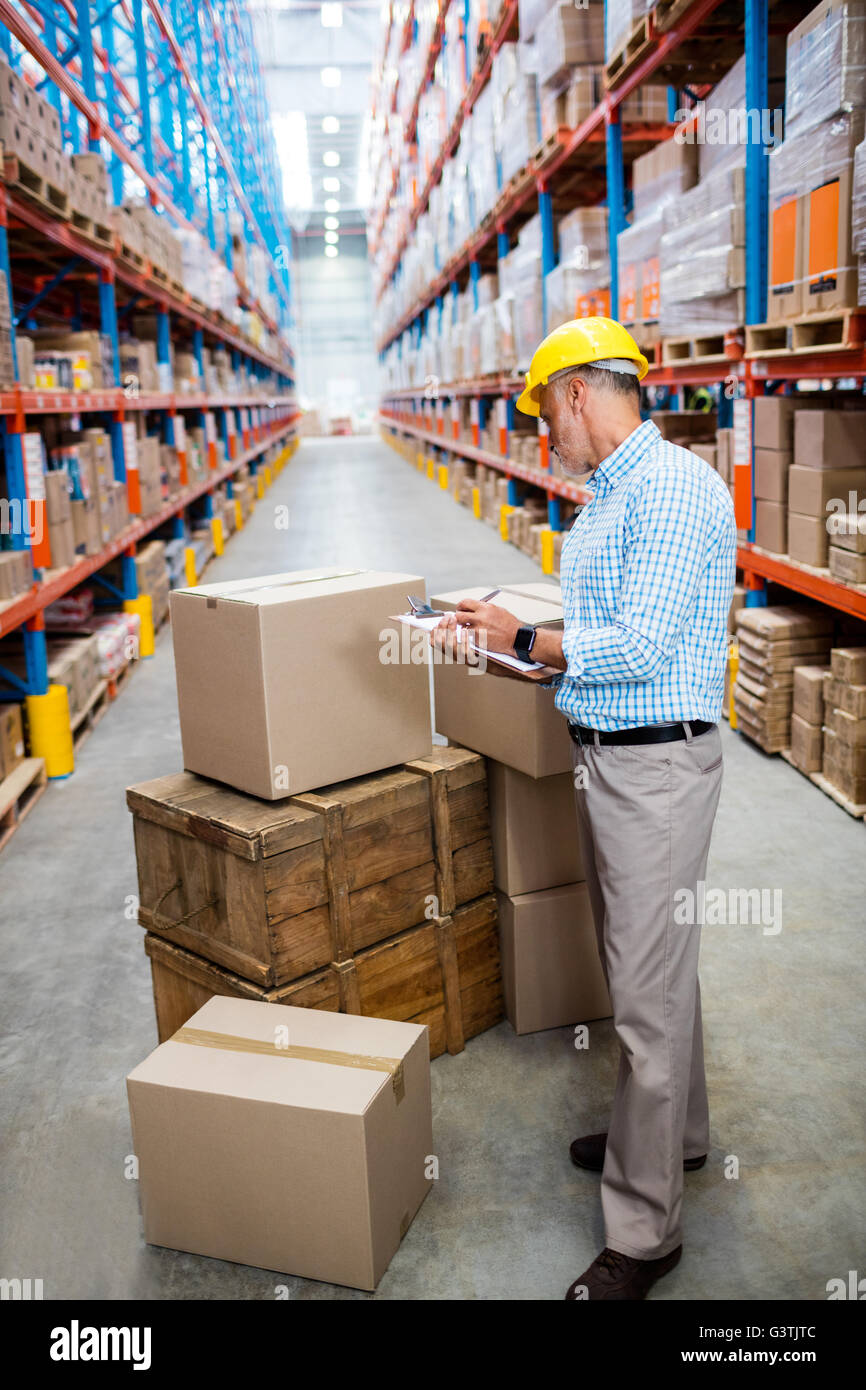 Warehouse worker writing on clipboard Stock Photo - Alamy