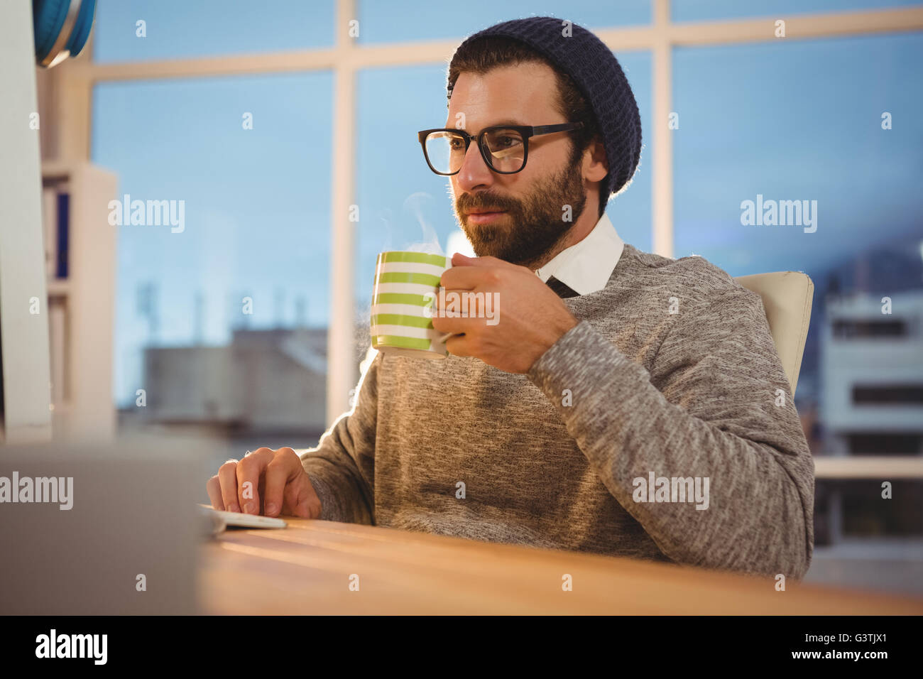 Hipster drinking coffee front of computer Stock Photo - Alamy