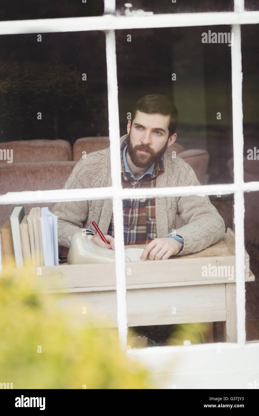 Handsome hipster man looking through window while writing Stock Photo ...