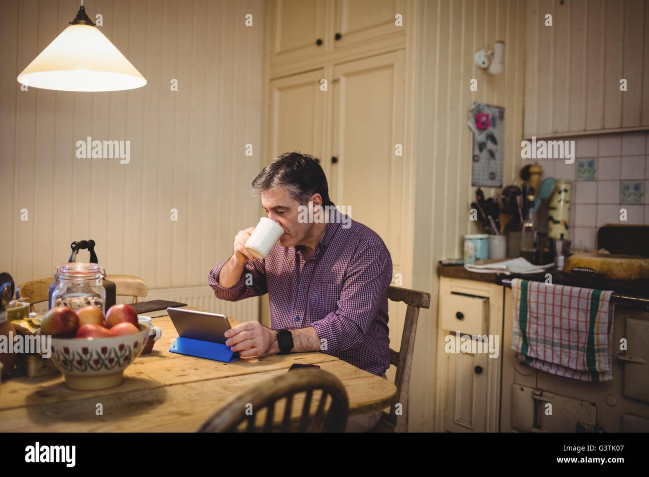 Mature man drinking while using tablet computer Stock Photo - Alamy