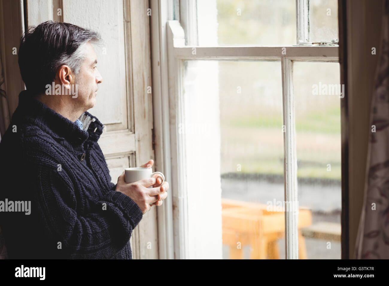 Thoughtful man looking through a window Stock Photo - Alamy