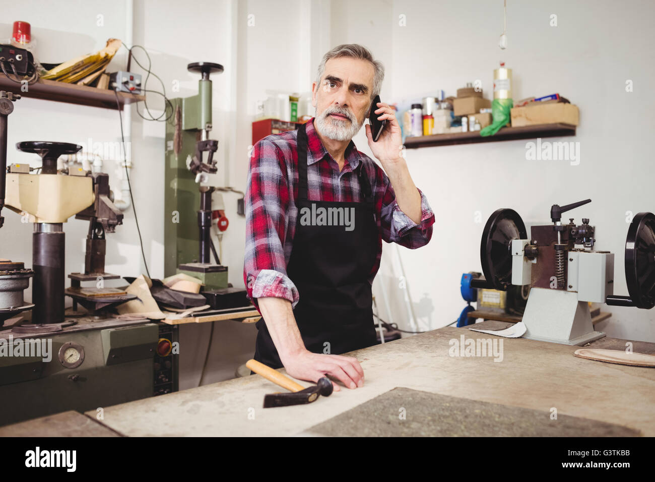 Cobbler calling with his mobile phone Stock Photo - Alamy