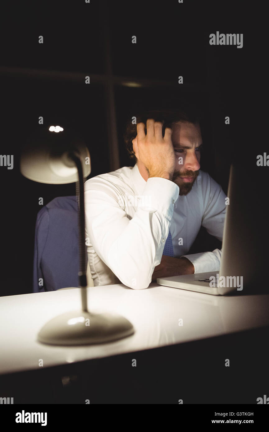 Overworked businessman looking at laptop at night Stock Photo - Alamy