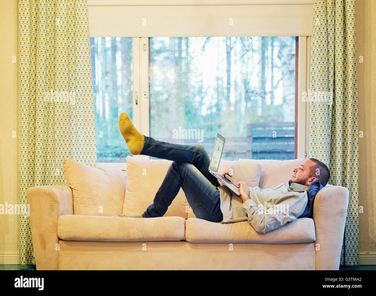Man lying on sofa using hi-res stock photography and images - Alamy