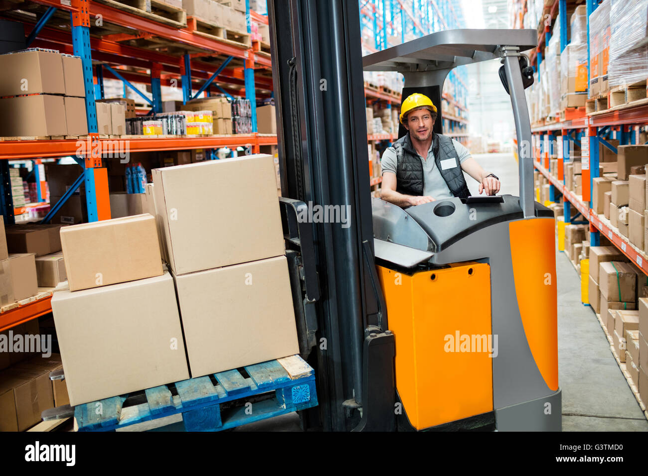 Warehouse worker driving forklift Stock Photo - Alamy