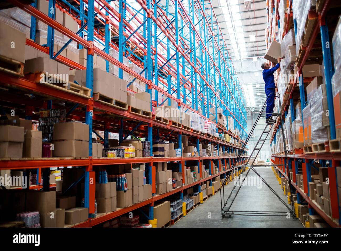 Man worker putting a box on a rack Stock Photo - Alamy