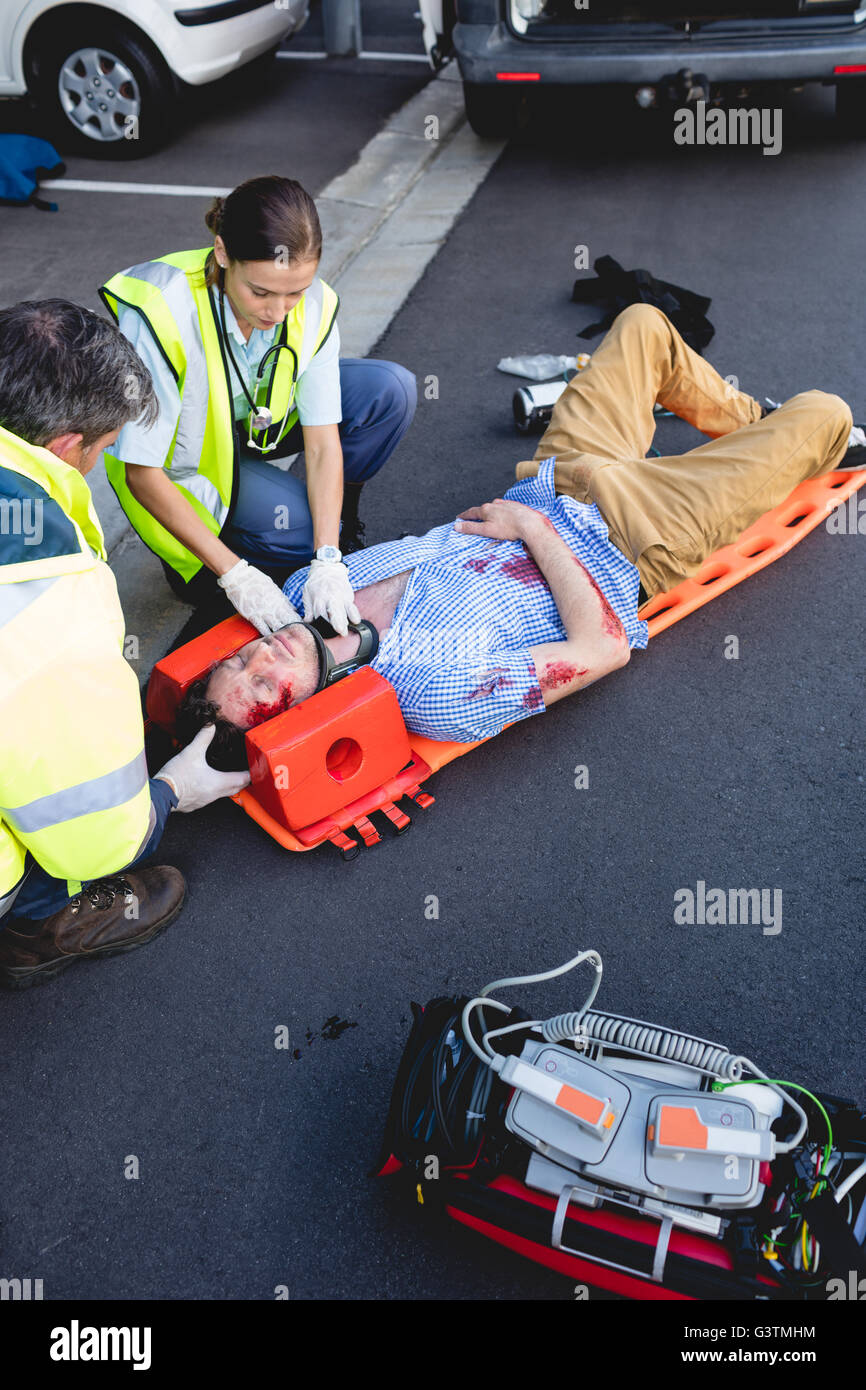 Ambulancemen healing injured man Stock Photo - Alamy