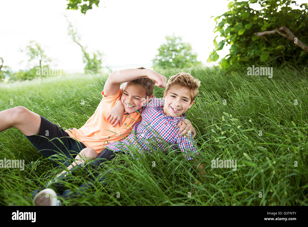 Two boys sitting and playing in long grass in the countryside Stock ...