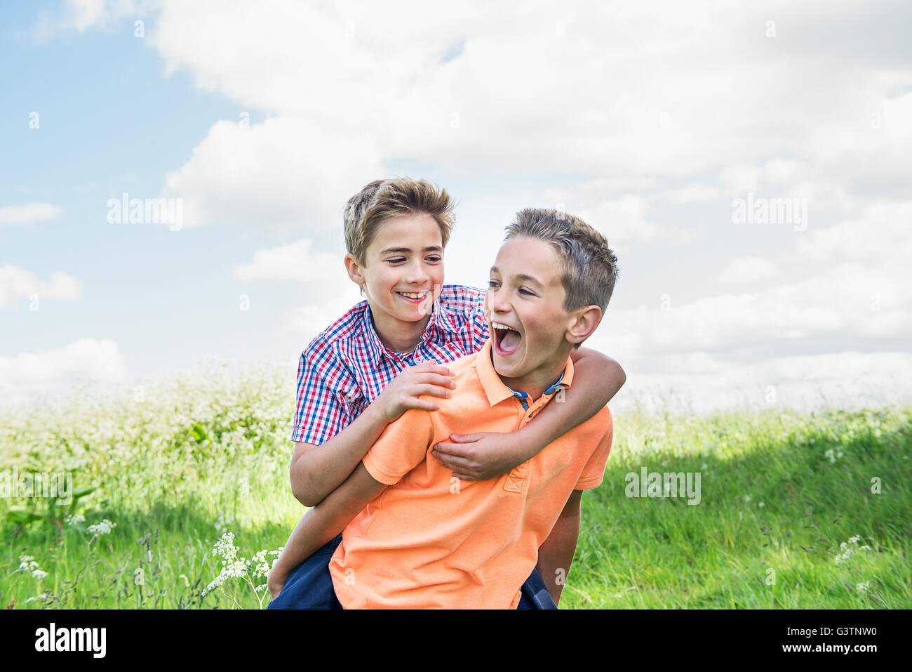 Two boys playing piggyback out in the countryside Stock Photo - Alamy