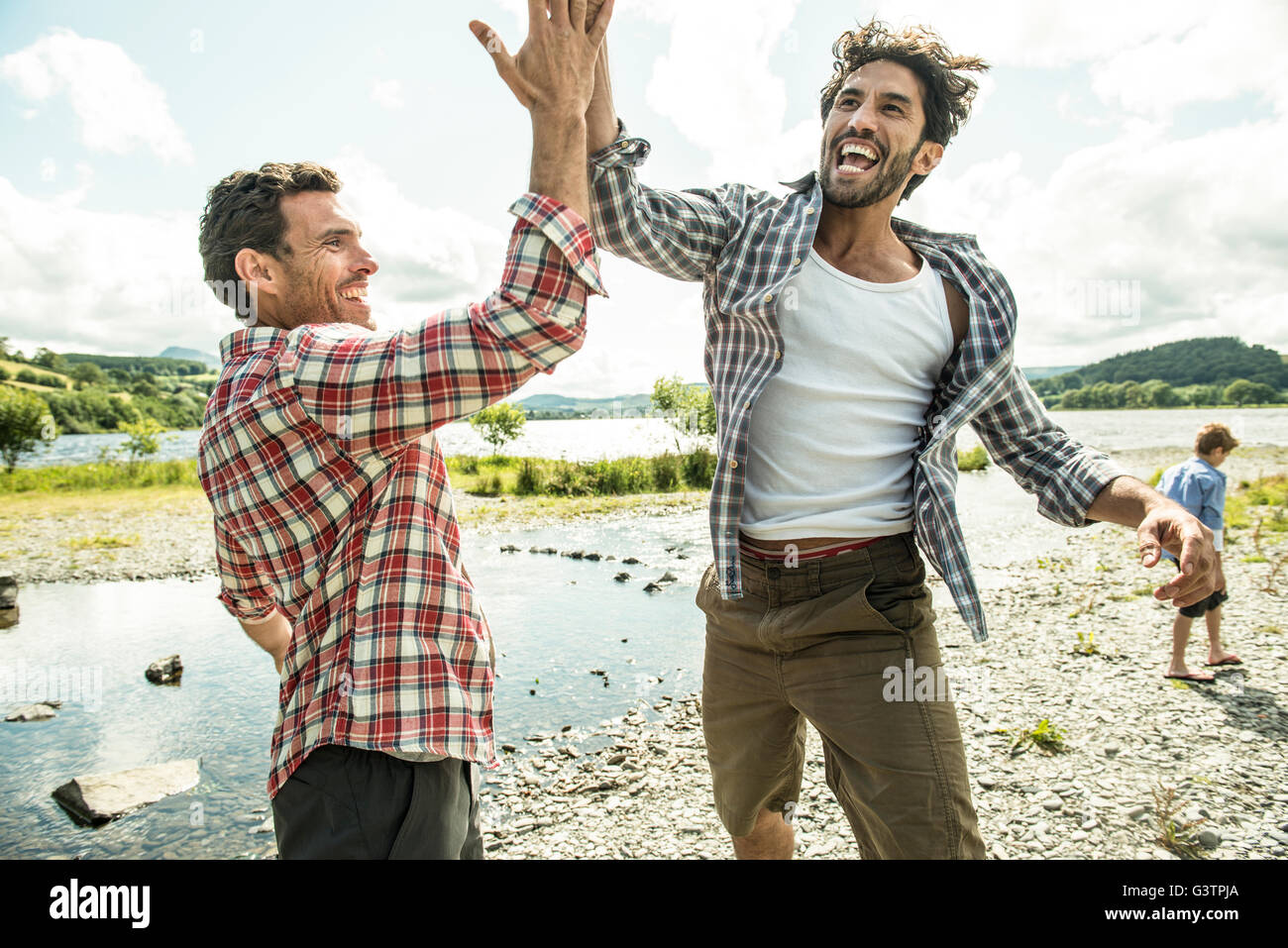 Two men leaping to high five near Bala Lake in Wales Stock Photo - Alamy
