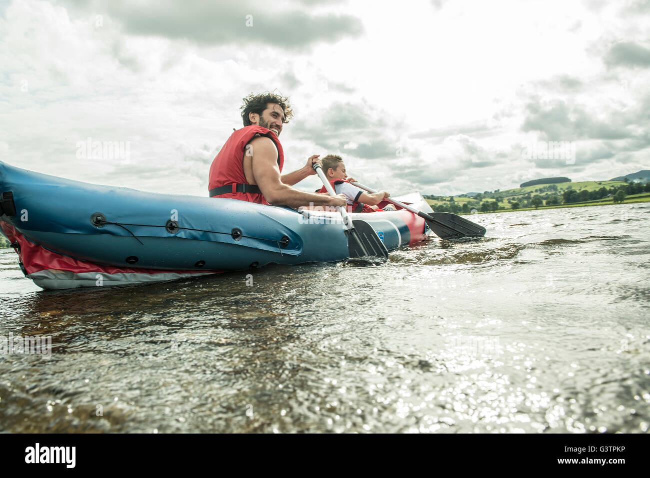 A man and a boy in a kayak paddling away from the shore on Bala Lake in ...