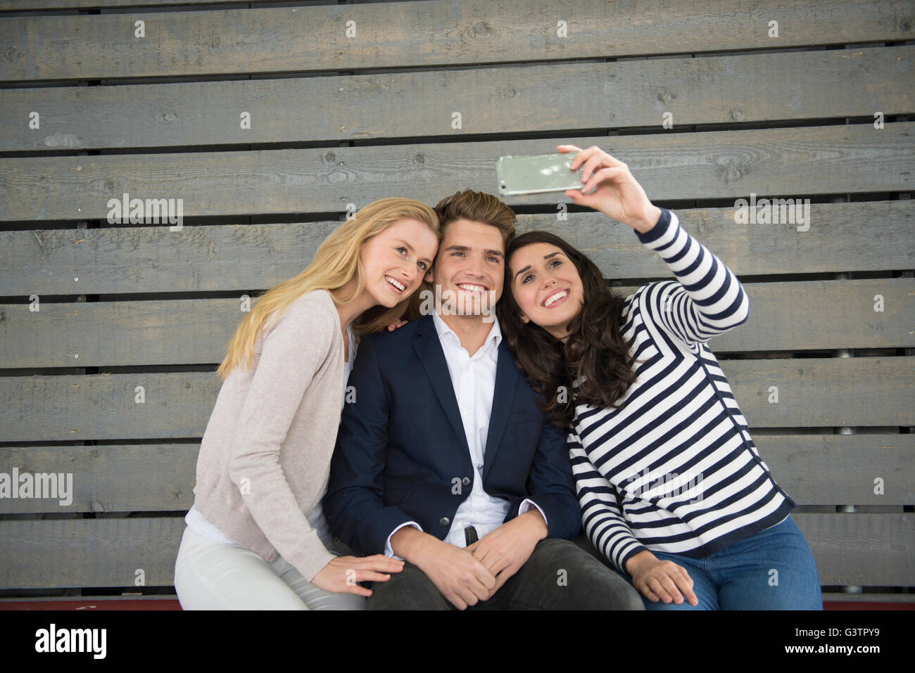 Three friends sitting on a bench taking a selfie on the South Bank in ...
