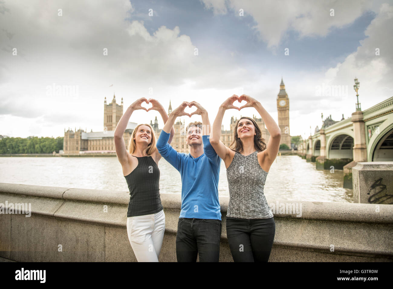 Three friends make a heart shape with their hands with the Houses of ...