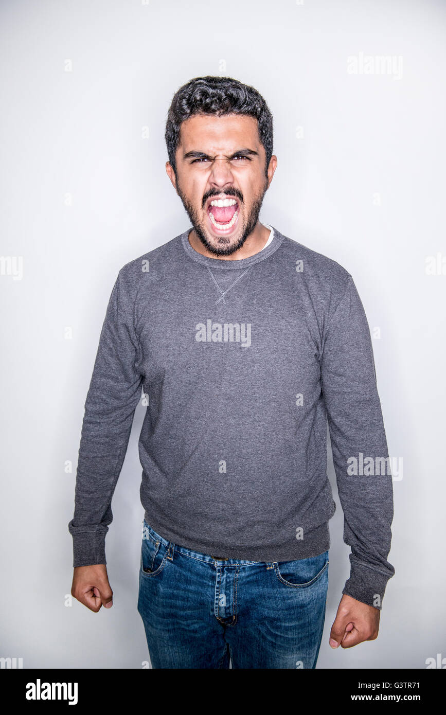 A young man posing in a studio looking angry Stock Photo - Alamy