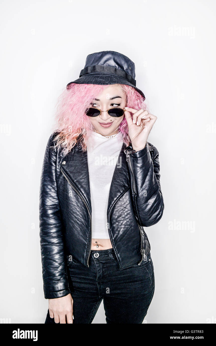 A young woman with pink hair posing in a studio looking cool Stock ...