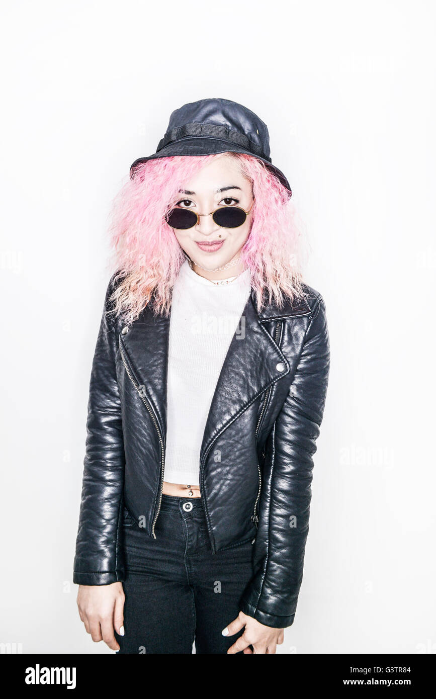 A young woman with pink hair posing in a studio looking cool Stock ...