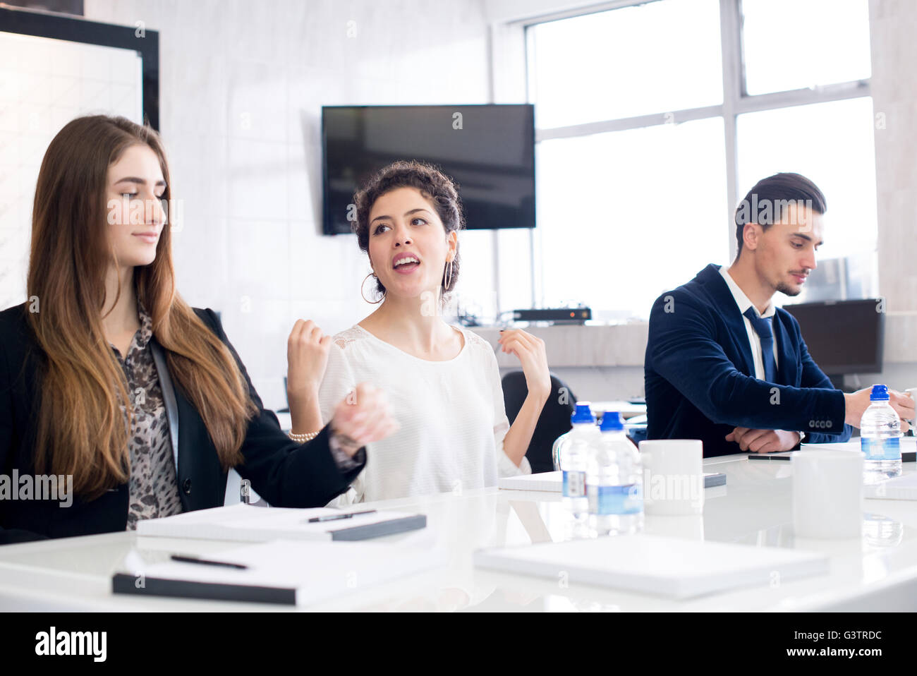 Three professional people sitting in an office environment having a ...