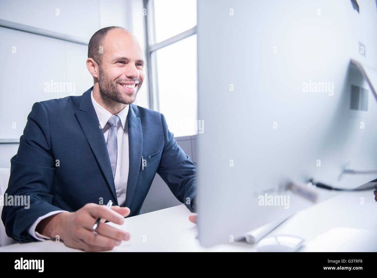 A professional man sitting in front of a computer in an office ...