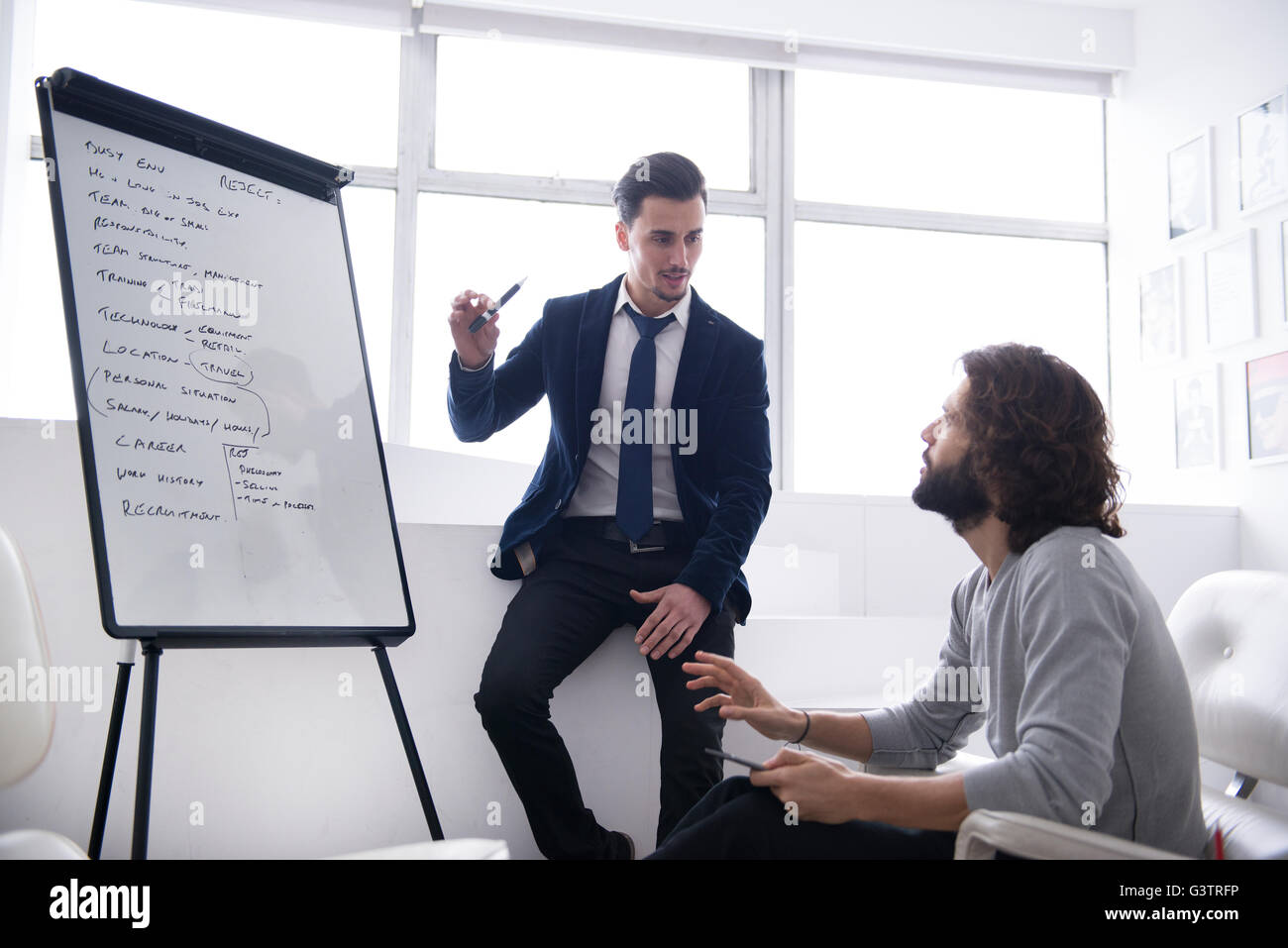 Two work colleagues discussing strategy in front of a flip chart in an ...
