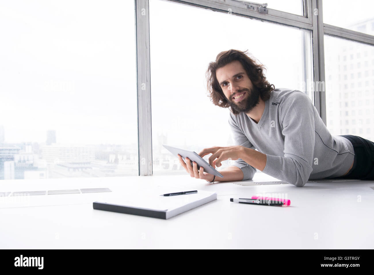 A professional man making notes on a tablet computer in a high rise ...