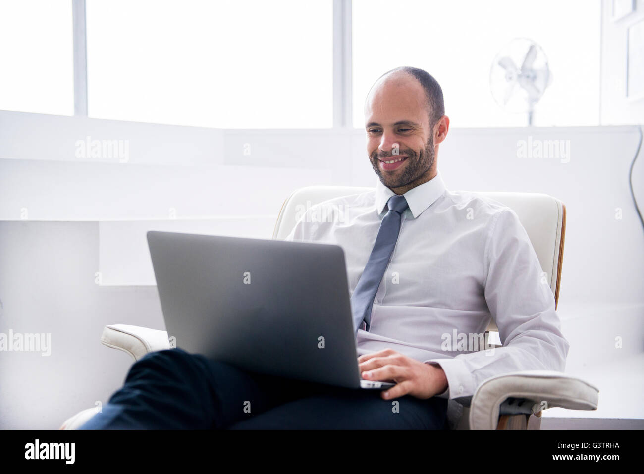 A professional man sitting making notes on a laptop in a business ...