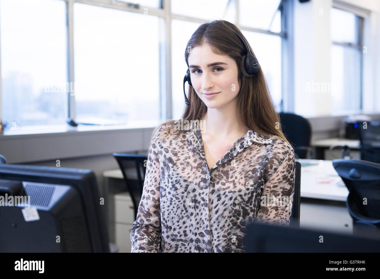 A young professional woman receiving a phone call on a headset in an ...