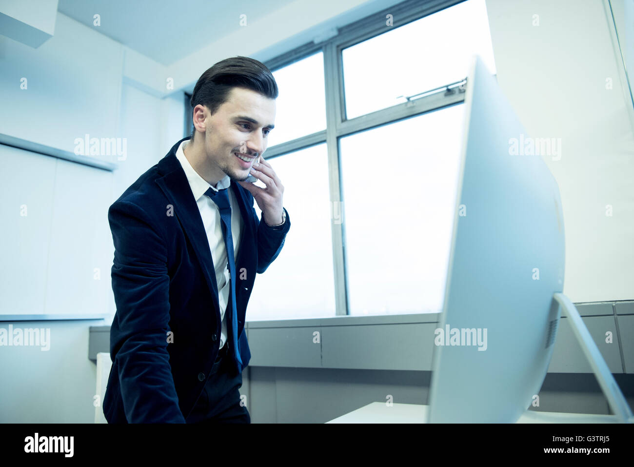 A professional man standing in front of a desktop computer in an office ...