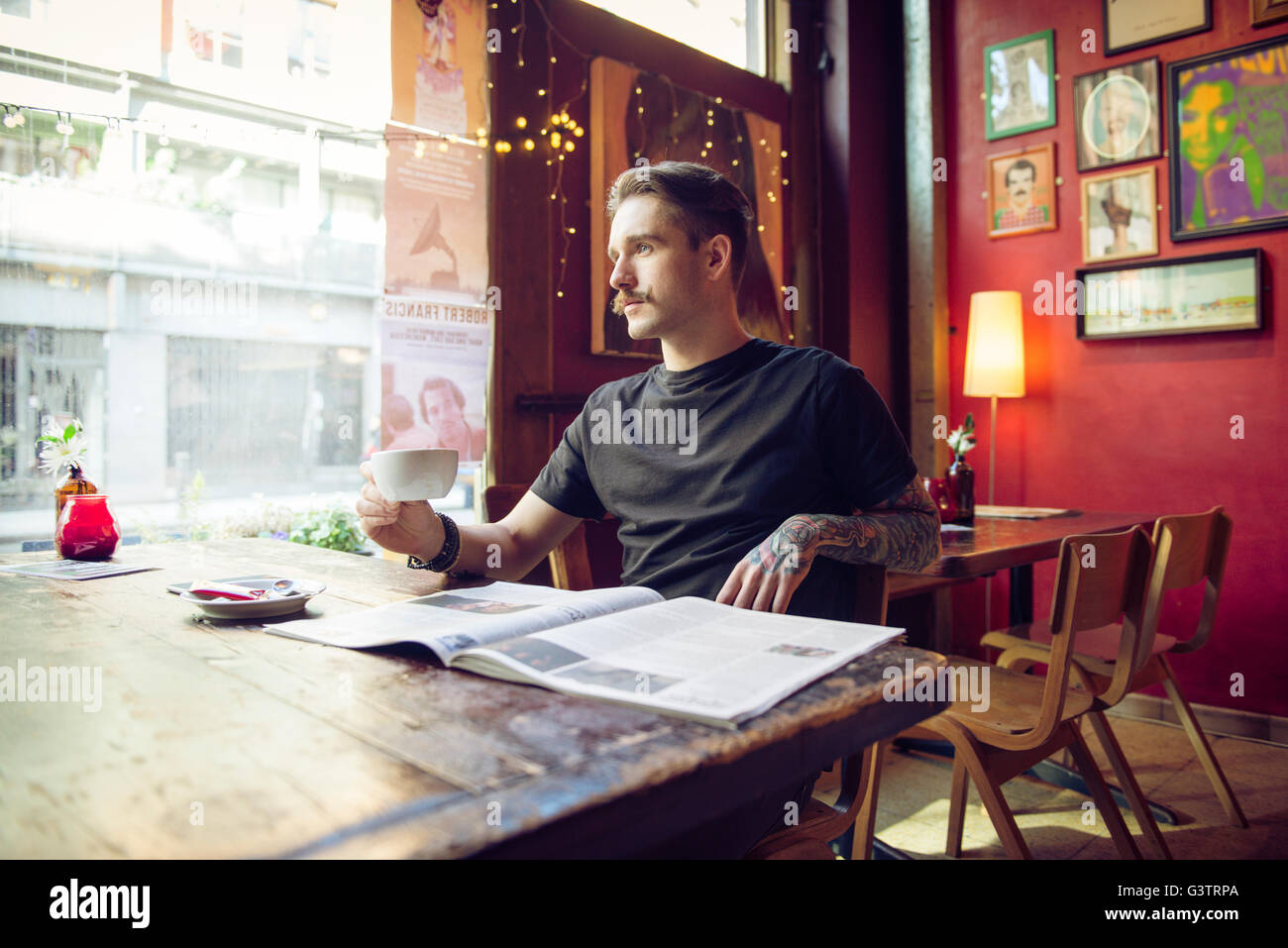 A young man sitting at a table in a coffee shop in Manchester Stock ...