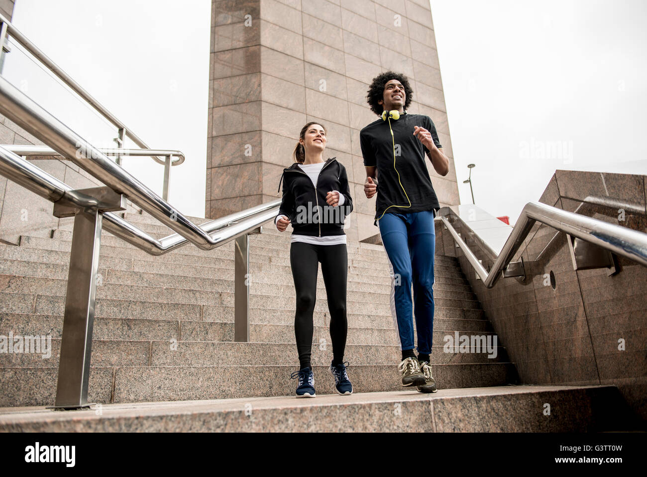 A young couple limbering up before a jog along the South Bank in London ...