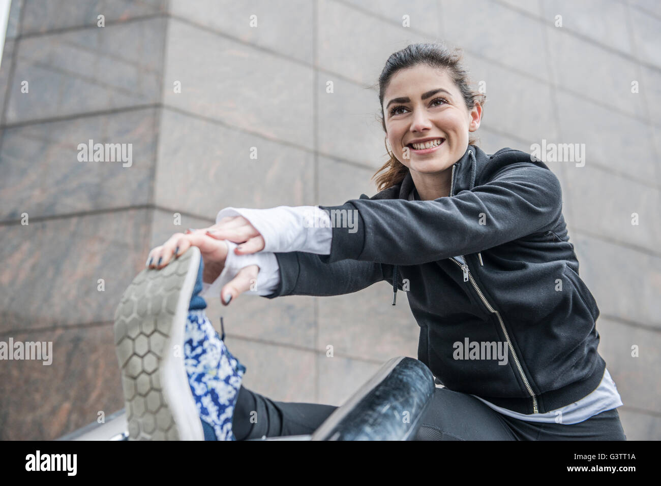 A young woman limbering up before a jog along the South Bank in London ...
