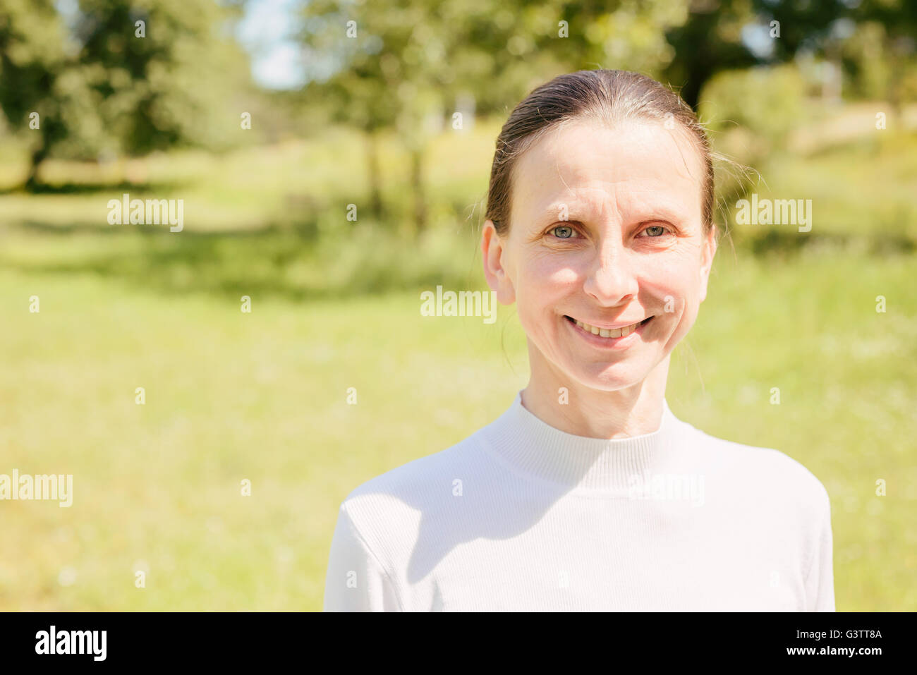 A warm portrait of a nice smiling senior woman in the park under the ...