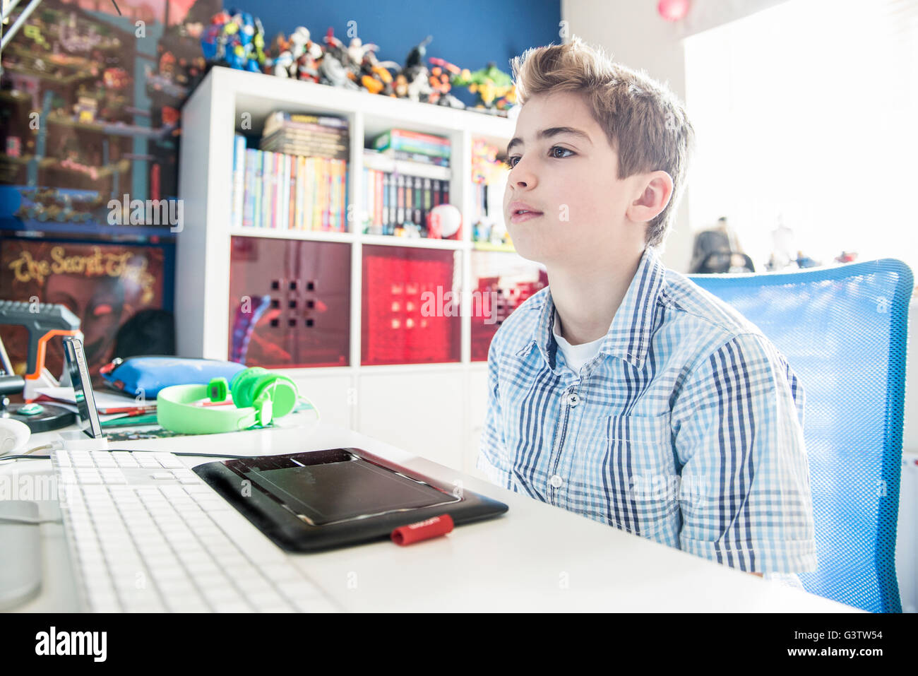 A ten year old boy sitting at a computer in his bedroom Stock Photo - Alamy