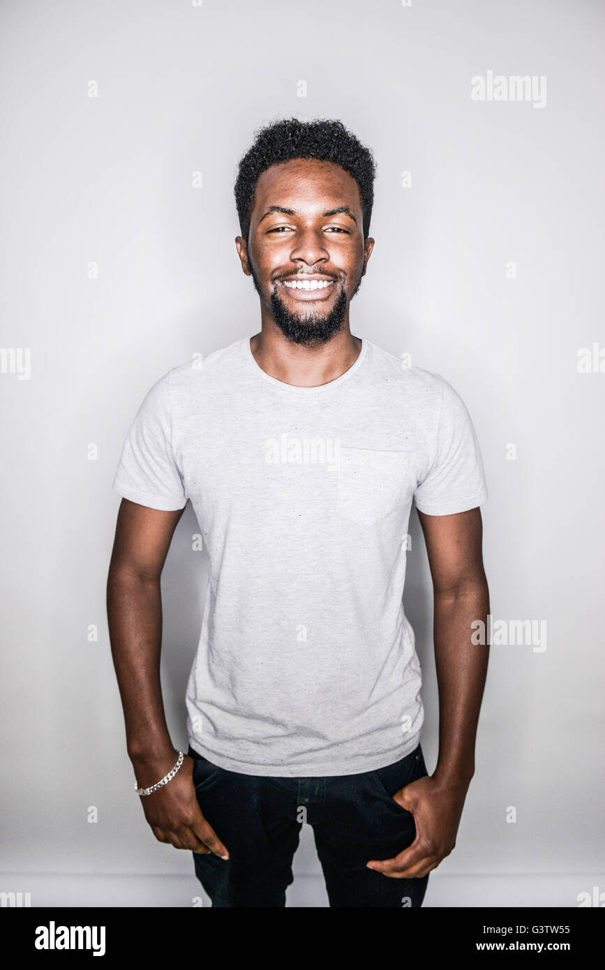 A young mixed race man posing in a studio looking happy Stock Photo - Alamy