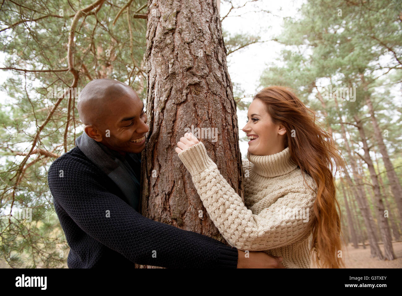 A young couple hugging a tree during a forest walk in Autumn Stock ...