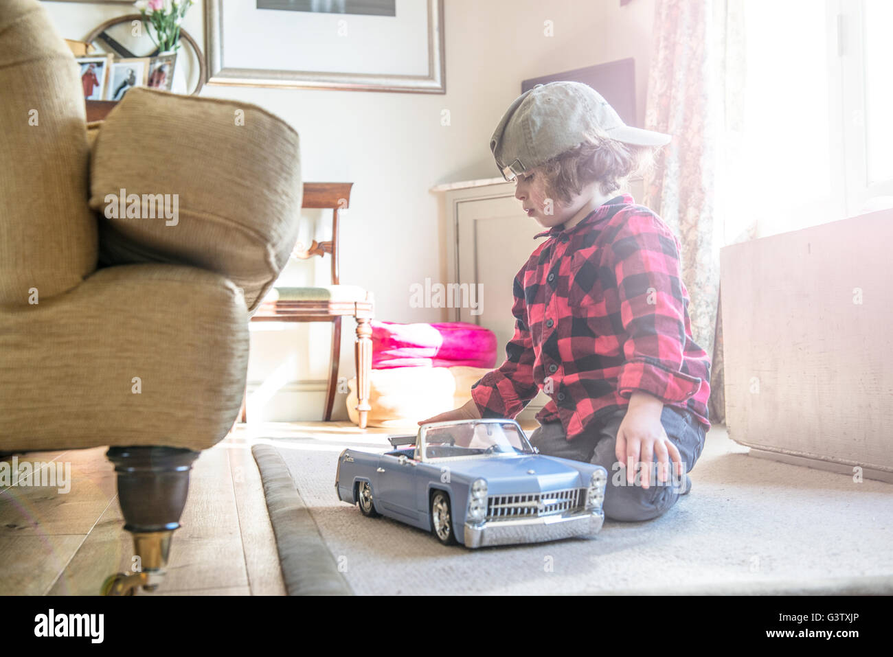 A four year old boy in a baseball cap playing with a toy car Stock ...