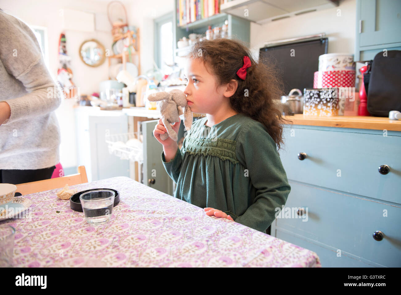 A Six Year Old Girl Standing At The Kitchen Table Holding A Toy Rabbit