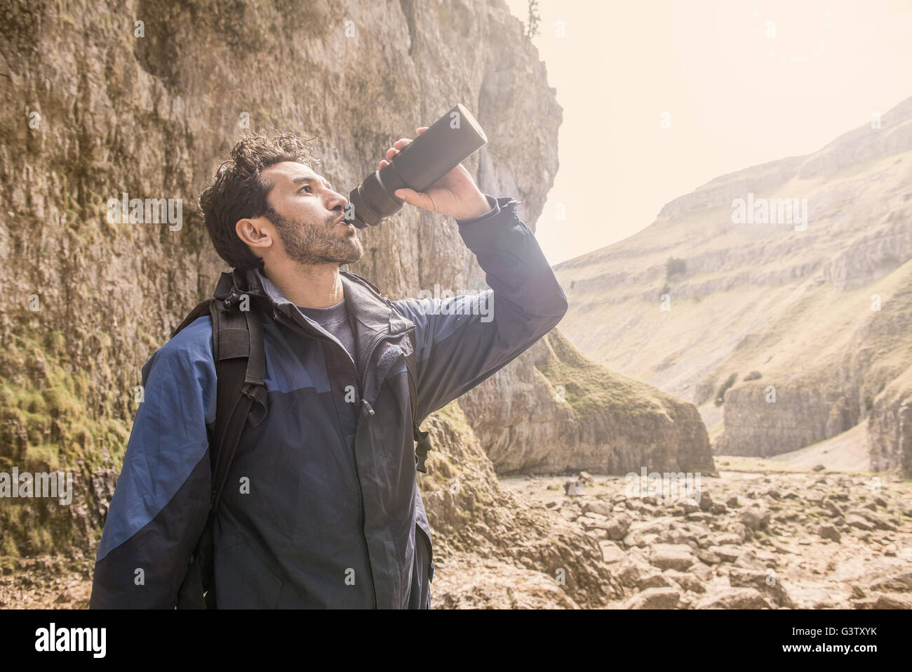 A mountaineer drinking from his water bottle fin rugged terrain Stock ...