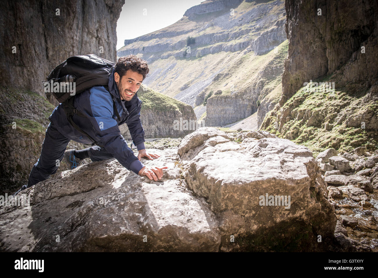 A mountaineer climbing over rocks in rugged terrain Stock Photo - Alamy