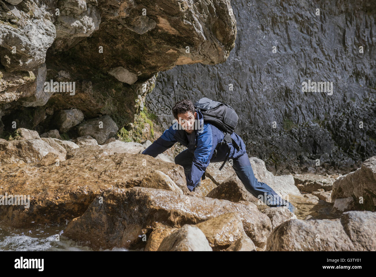 A mountaineer climbing over rocks in rugged terrain Stock Photo - Alamy