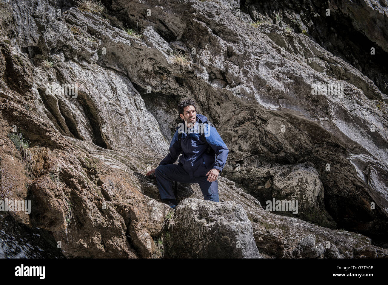 A mountaineer climbing over rocks in rugged terrain Stock Photo - Alamy