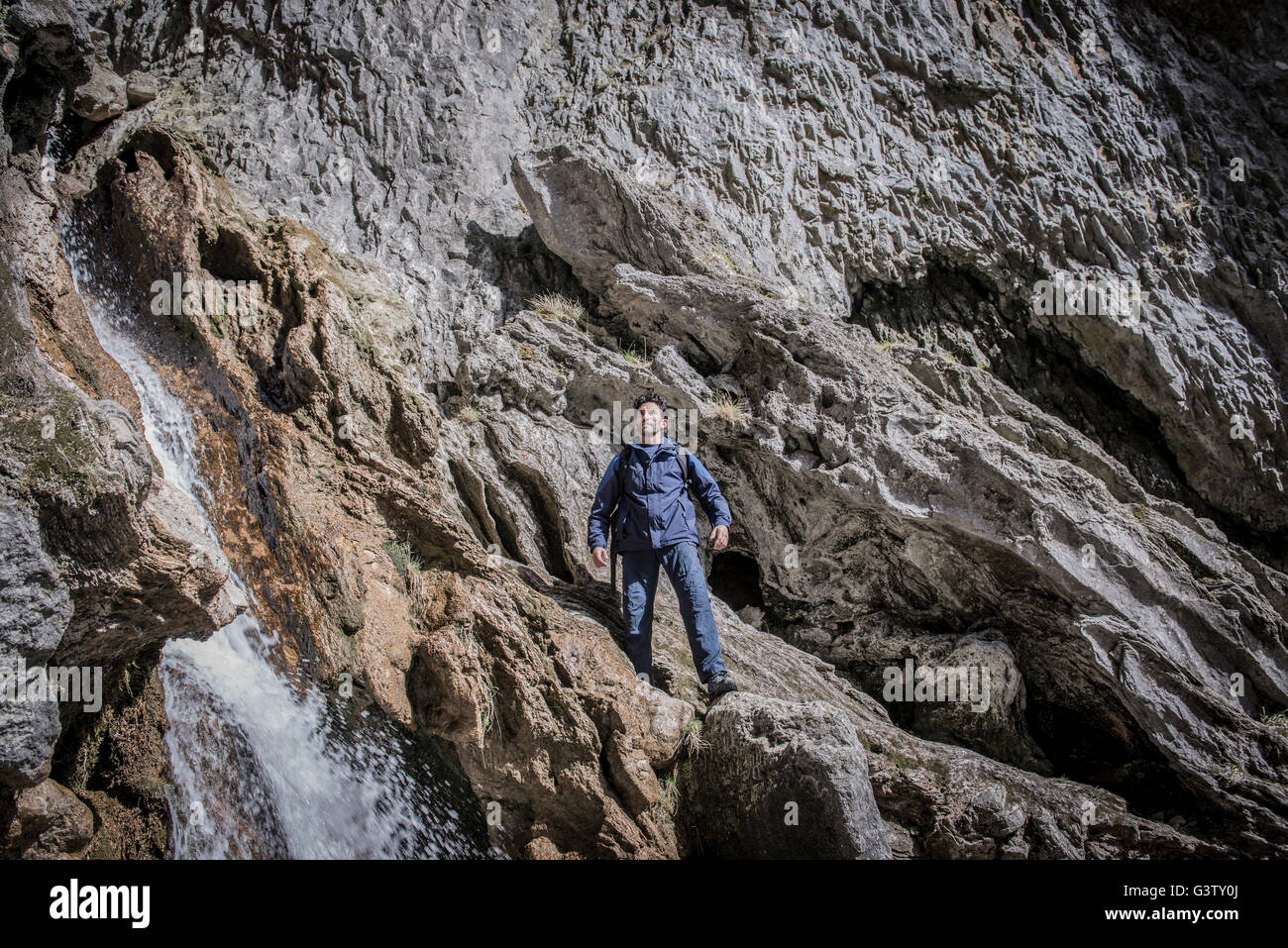 A mountaineer climbing over rocks in rugged terrain Stock Photo - Alamy