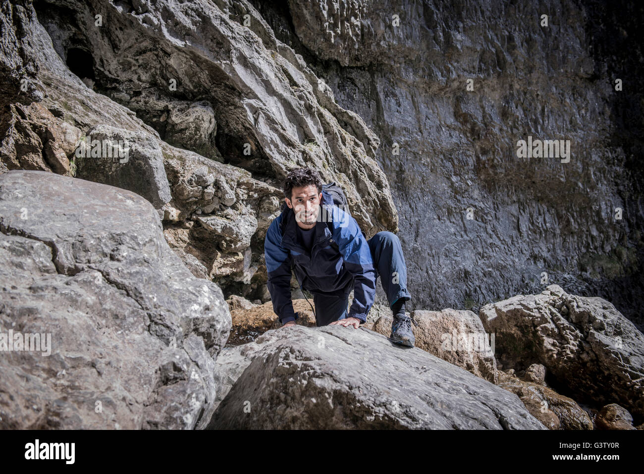 A mountaineer climbing over rocks in rugged terrain Stock Photo - Alamy