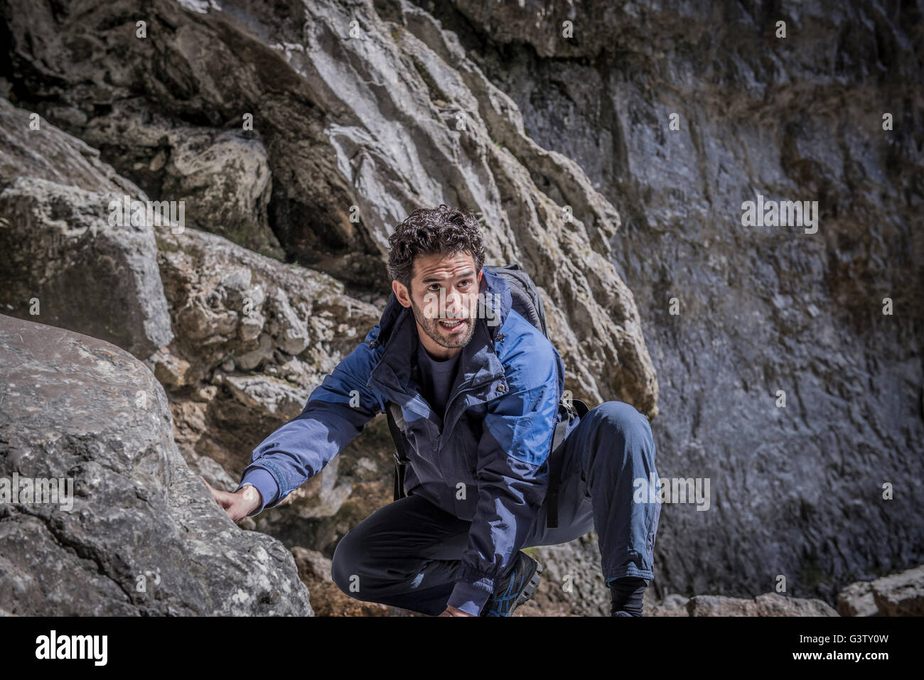 A mountaineer climbing over rocks in rugged terrain Stock Photo - Alamy